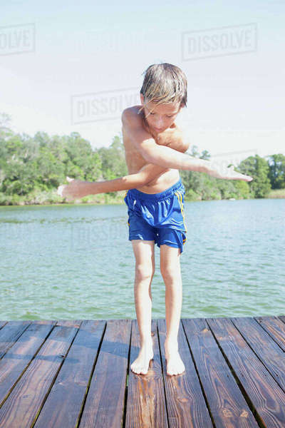 Boy swinging arms by jetty - Royalty-free Stock Photo | Dissolve