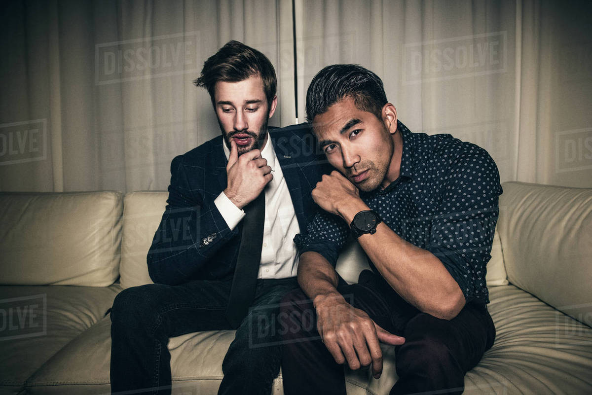 Two young men sitting on sofa - Royalty-free Stock Photo | Dissolve