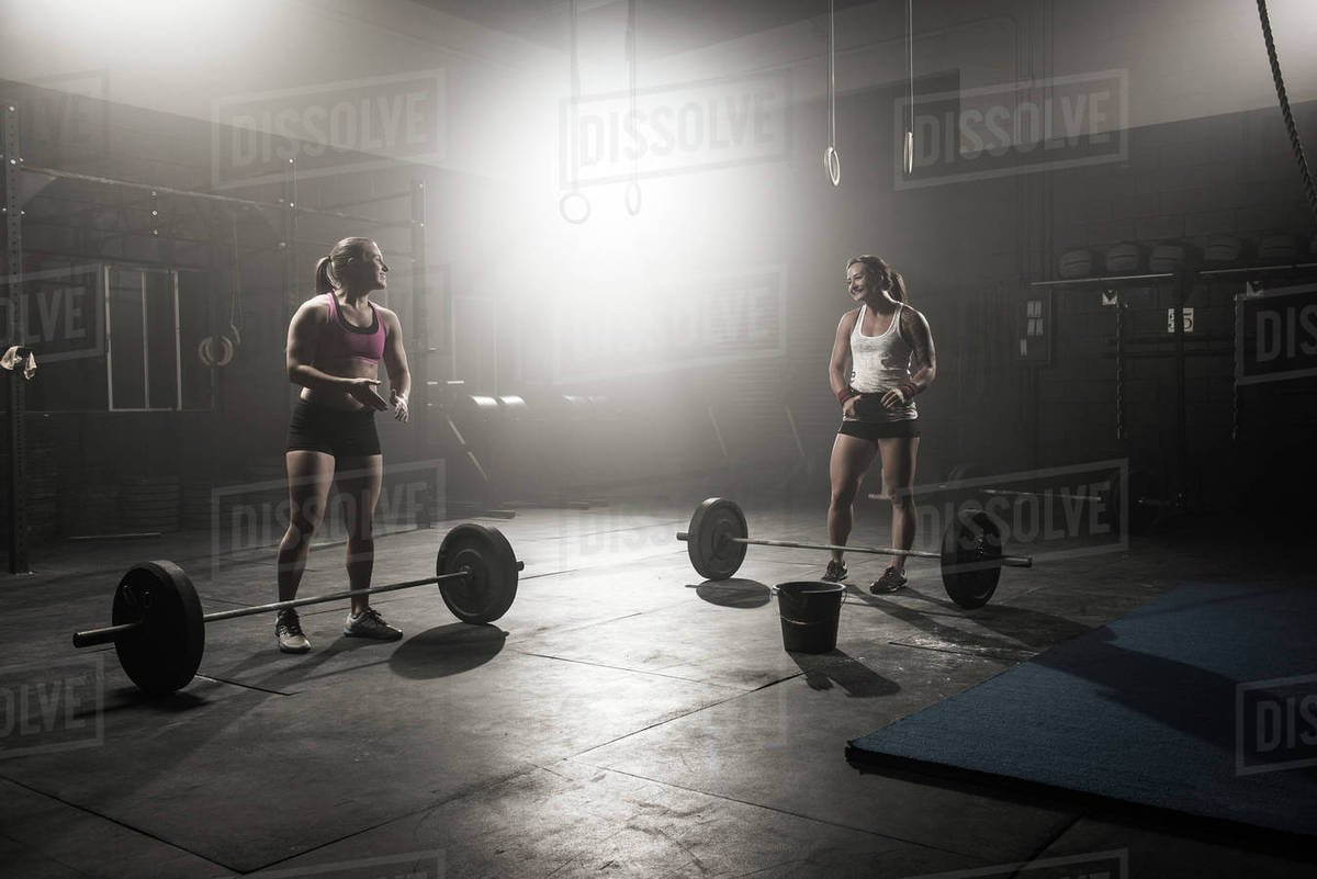 Two young women preparing to lift barbells - Stock Photo - Dissolve