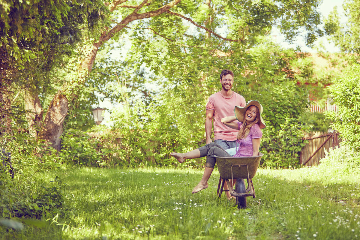 Young couple, man pushing woman in wheelbarrow, laughing - Stock Photo ...
