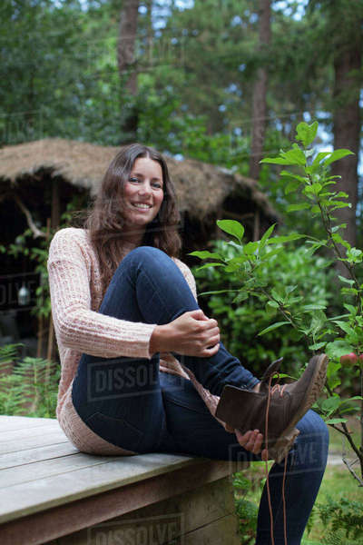 Portrait of young woman removing boots on chalet porch - Royalty-free ...