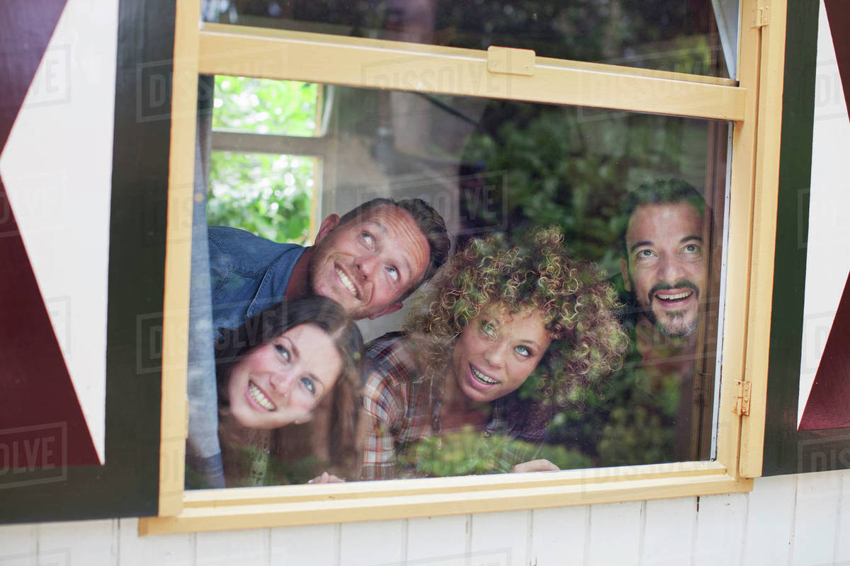 Four adult friends posing whilst looking through cabin window - Royalty ...
