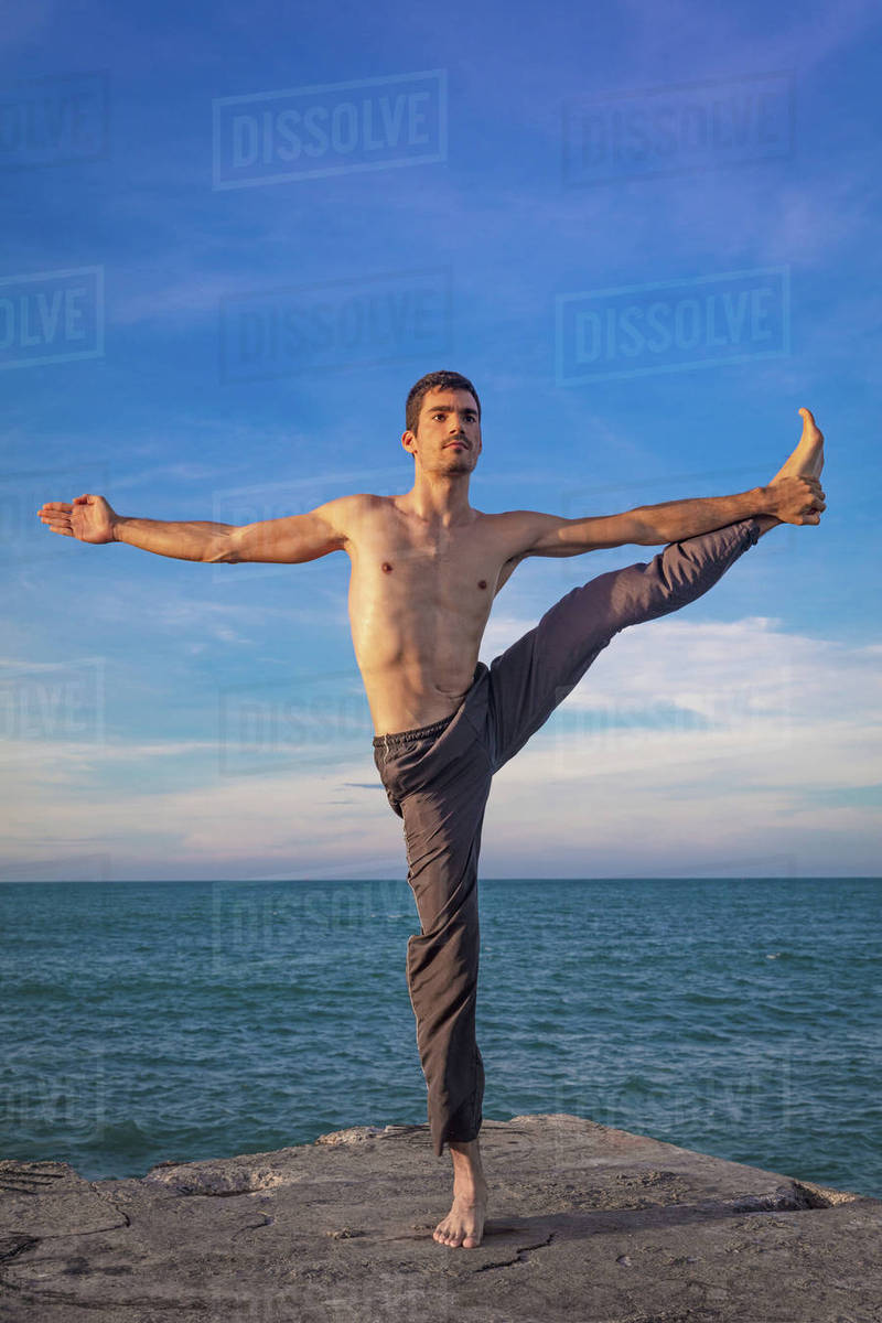 Young man outdoors, in yoga position, balancing on one leg - Royalty ...