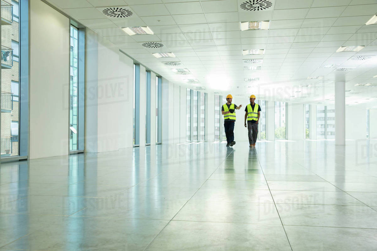 Two construction workers walking through empty office space - Royalty ...