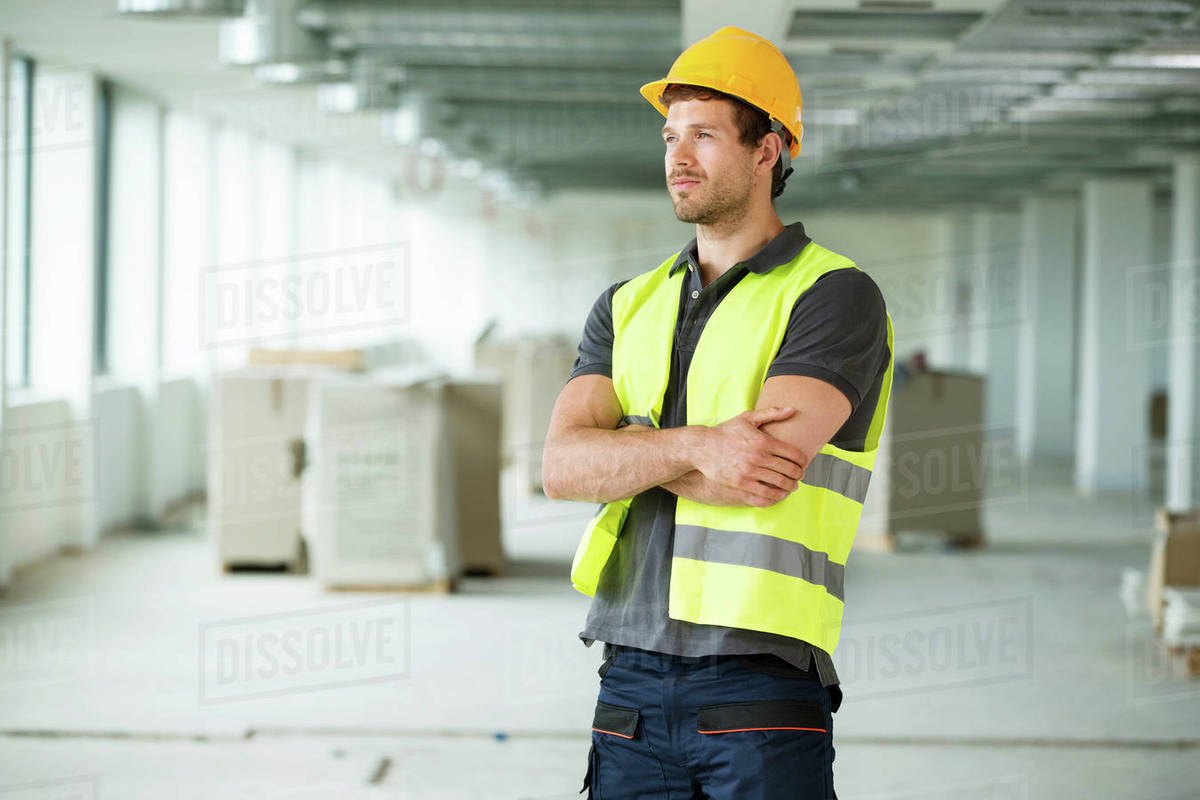 Workers wearing hi vis vest, standing in newly constructed office space ...