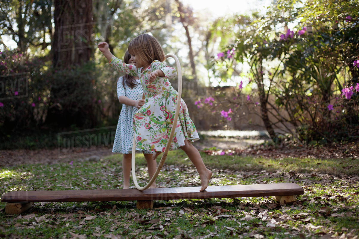 Girl running through plastic hoop in garden - Stock Photo - Dissolve