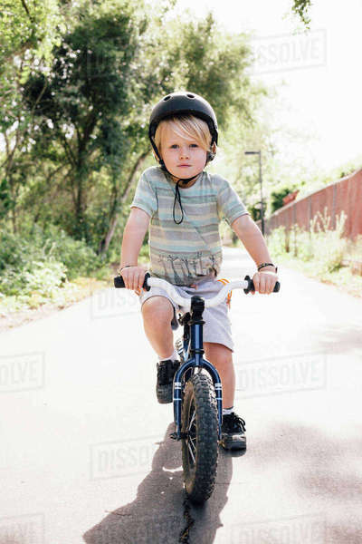 Portrait of young boy riding bicycle outdoors - Stock Photo - Dissolve