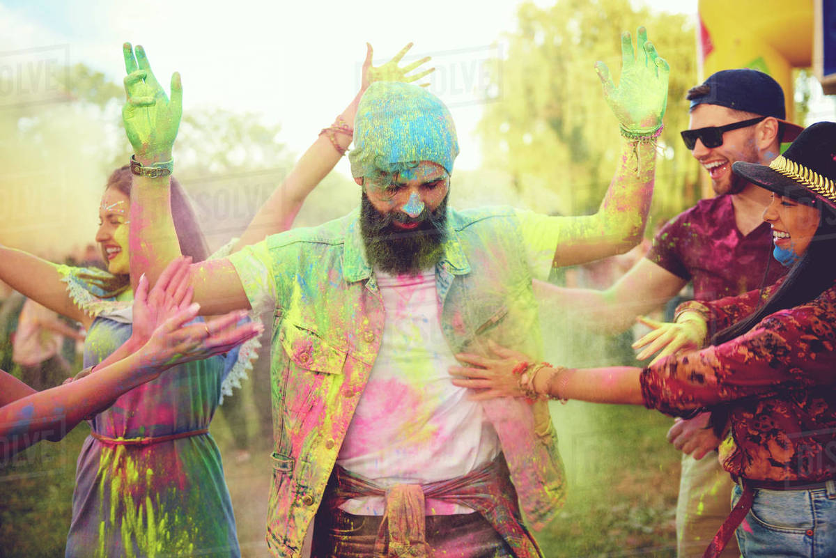 Young adult friends throwing coloured chalk powder and dancing at ...