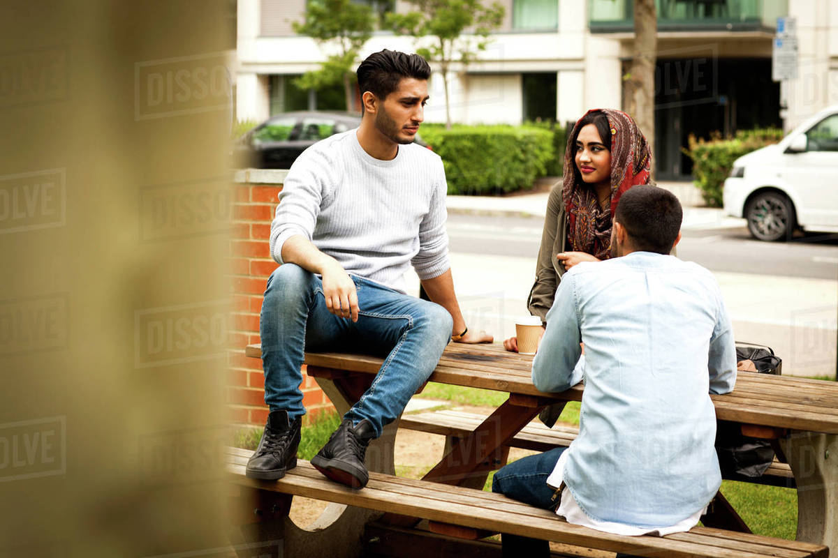 Friends enjoying coffee together on park bench - Royalty-free Stock ...