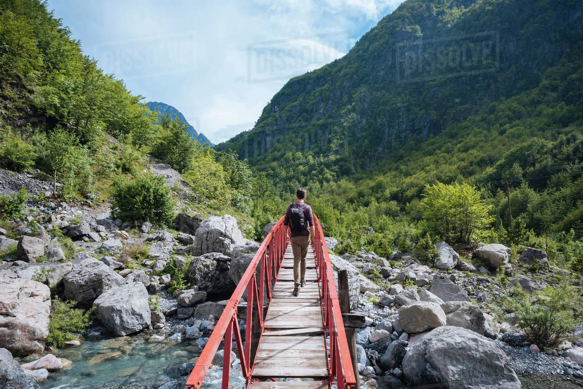 Rear view of man crossing bridge, Accursed mountains, Theth, Shkoder ...