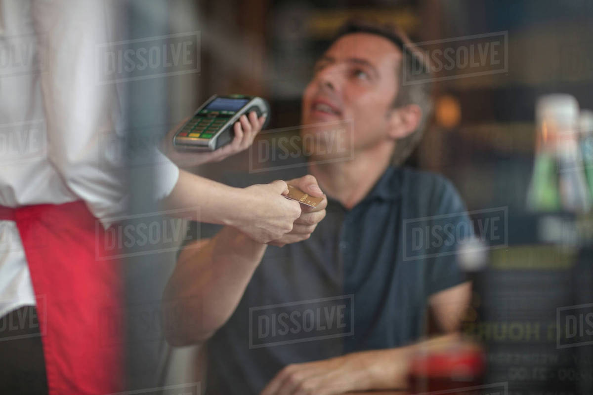 Customer handing credit card to waitress for payment on card machine ...