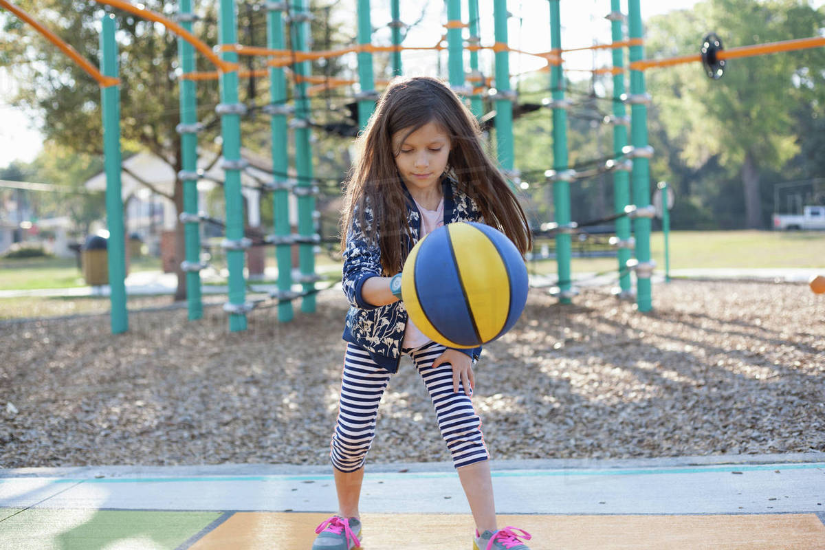 Girl bouncing basketball in playground - Stock Photo - Dissolve