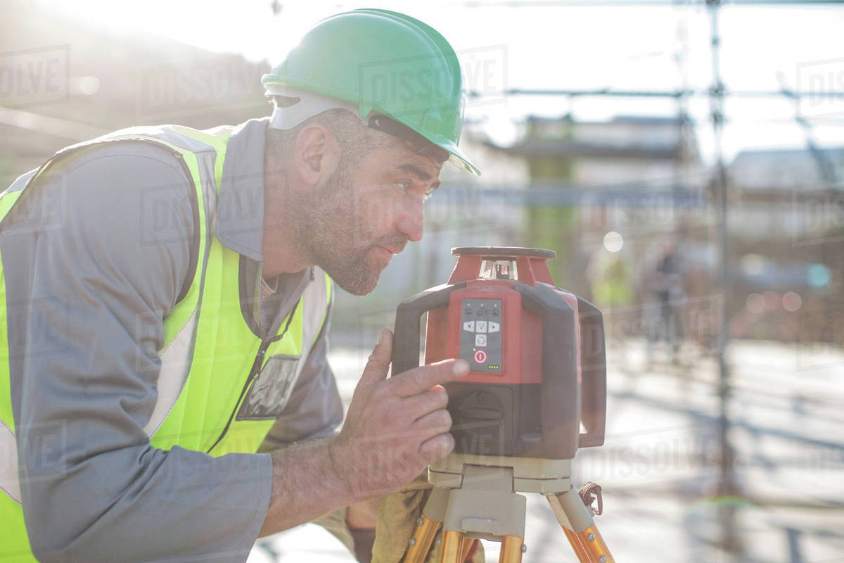 Construction worker using surveying equipment - Stock Photo - Dissolve