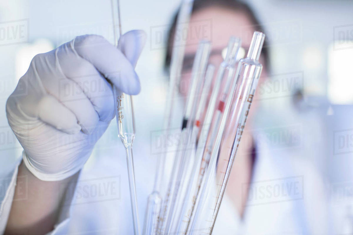 Laboratory worker choosing pipette, close-up - Stock Photo - Dissolve