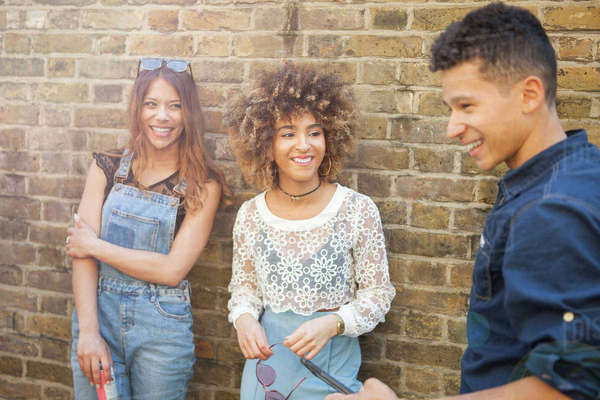Three friends standing together in street, laughing - Stock Photo ...