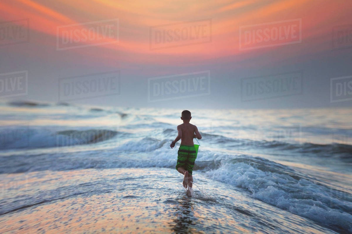 Boy running into sea at sunset, North Myrtle Beach, South Carolina ...