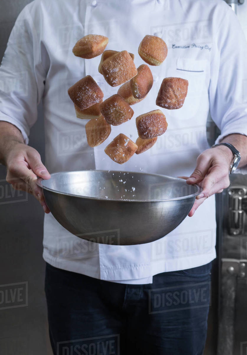 Cropped view of chef tossing doughnuts and sugar in mixing bowl - Stock ...