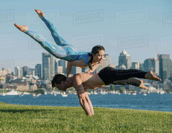 Teenage girl and young man, outdoors, man balancing on hands, girl ...