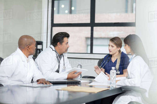 Group of doctors sitting at table, having discussion - Royalty-free ...