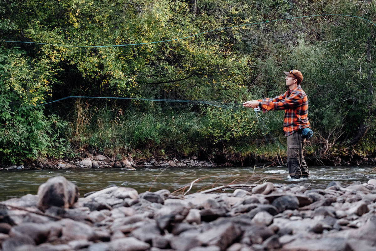 Man wading in river, fishing - Stock Photo - Dissolve