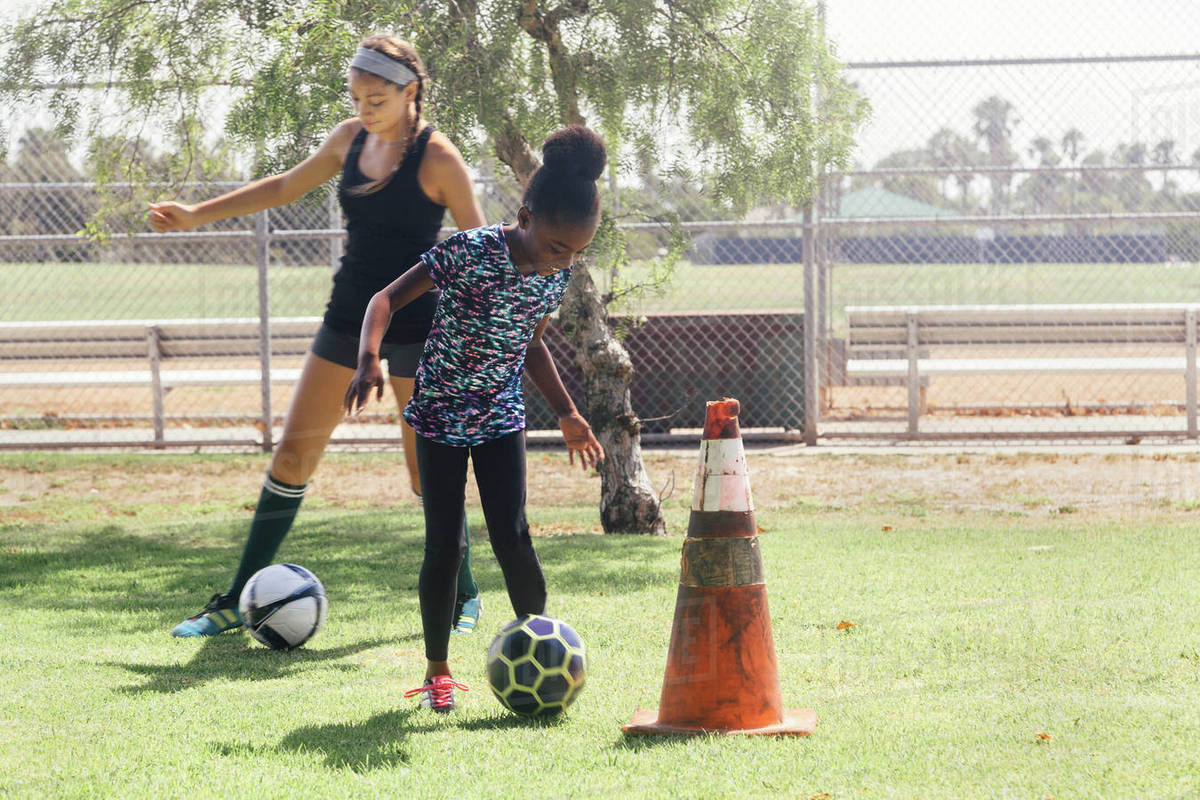 Schoolgirls doing dribbling soccer ball practice on school sports field ...