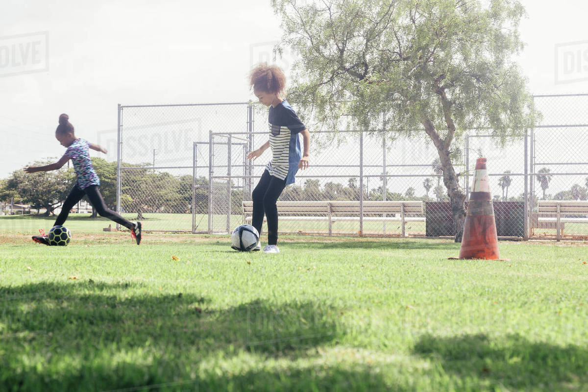 Schoolgirls doing dribbling soccer ball practice on school sports field ...