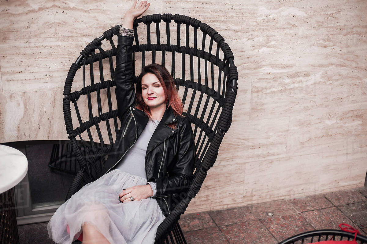 Portrait of woman sitting in chair with arm raised - Royalty-free Stock ...