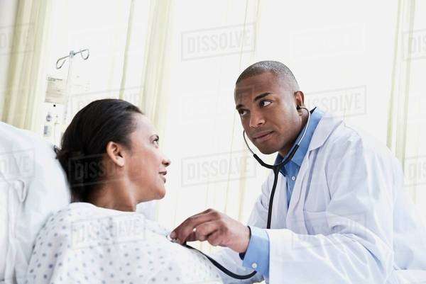Male doctor checking female patient with stethoscope - Royalty-free ...