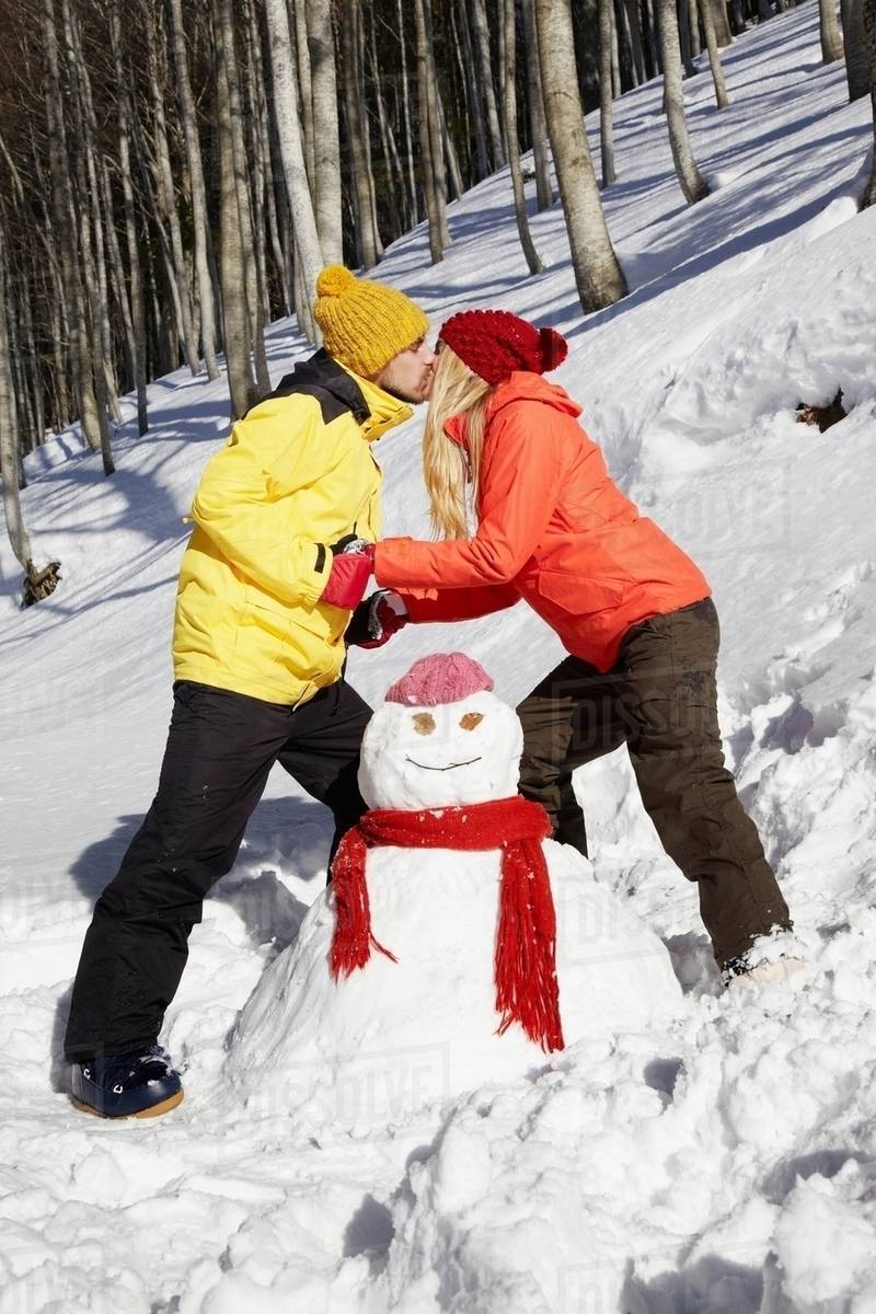 Couple kissing by snowman - Stock Photo - Dissolve