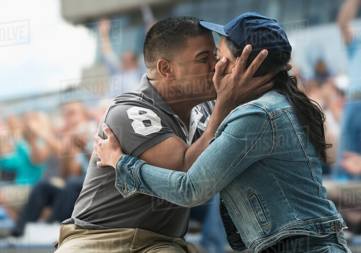 Couple kissing at sports game - Stock Photo - Dissolve