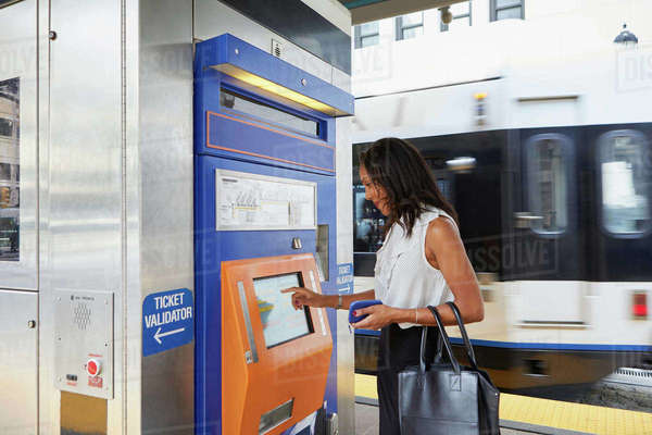 Businesswoman buying train ticket at machine - Stock Photo - Dissolve
