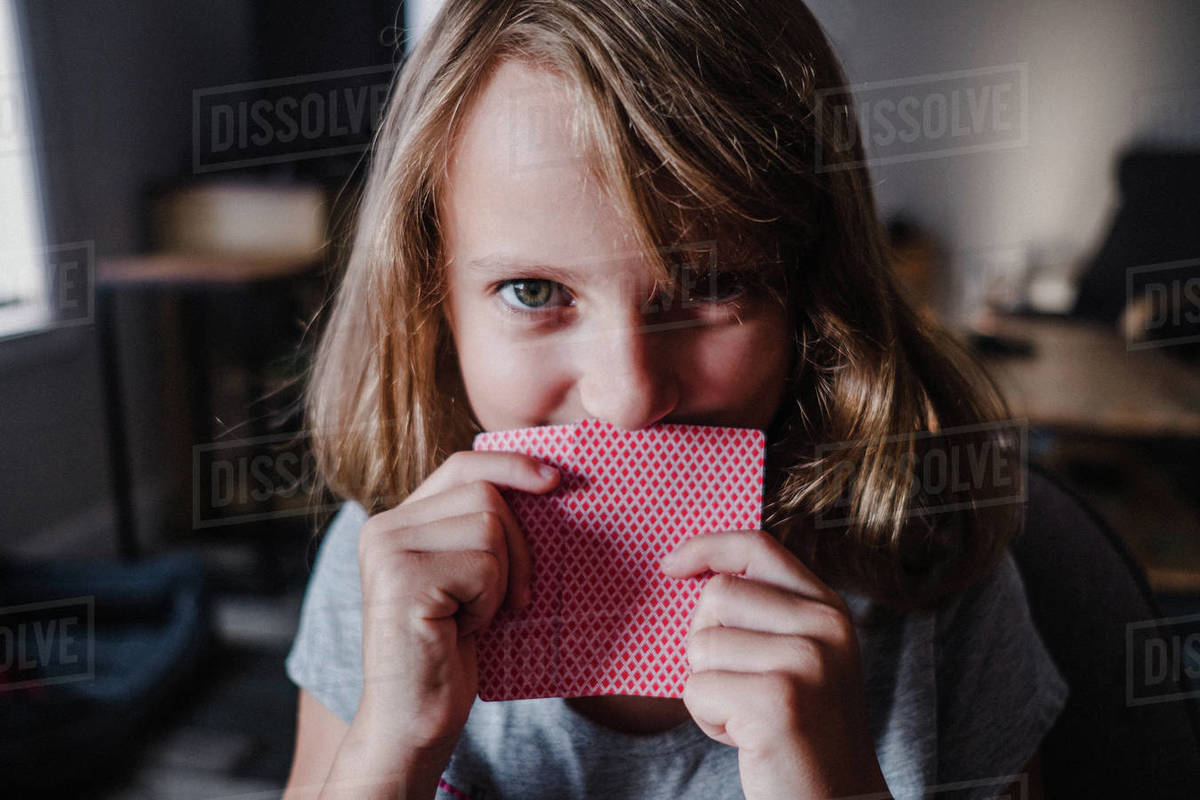 Girl hiding behind playing cards in living room, portrait - Stock Photo ...
