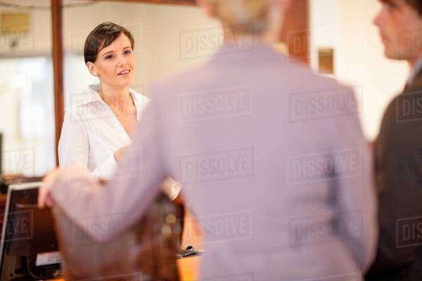 Hotel receptionist talking to guests - Stock Photo - Dissolve