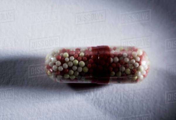 Capsule containing tiny pills - Stock Photo - Dissolve