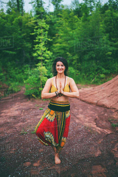 Woman doing tree pose in forest - Stock Photo - Dissolve