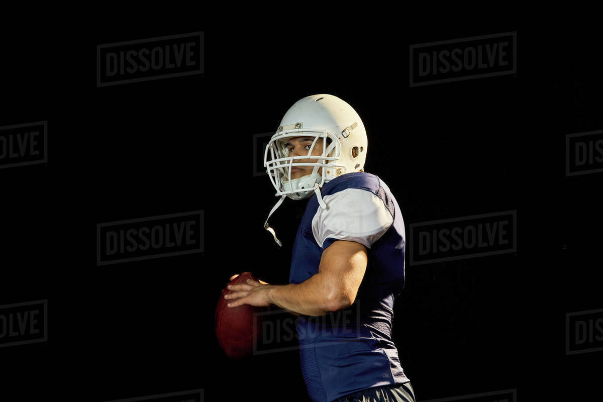 Portrait of quarterback with football, black background - Stock Photo ...