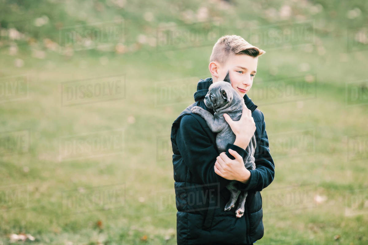 Boy carrying puppy outdoors - Stock Photo - Dissolve
