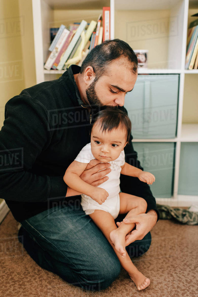 Father sitting on nursery floor with baby son on his lap - Royalty-free ...
