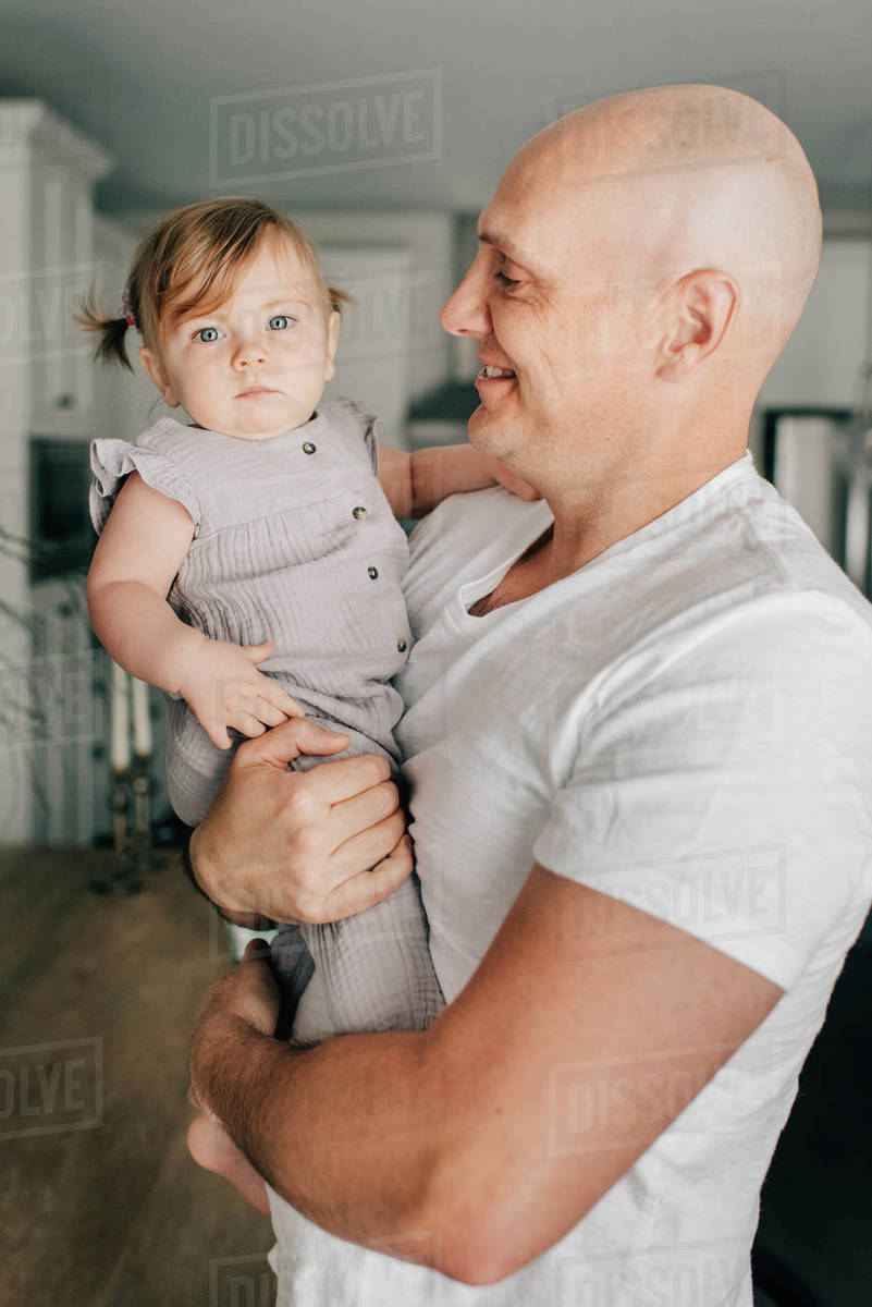 Father carrying baby daughter in living room, portrait - Stock Photo ...