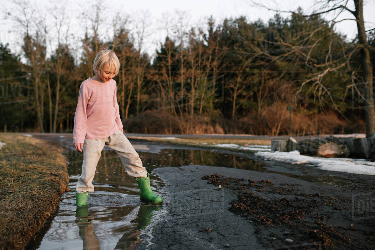 Boy stepping ankle deep in rural meltwater puddle - Royalty-free Stock ...