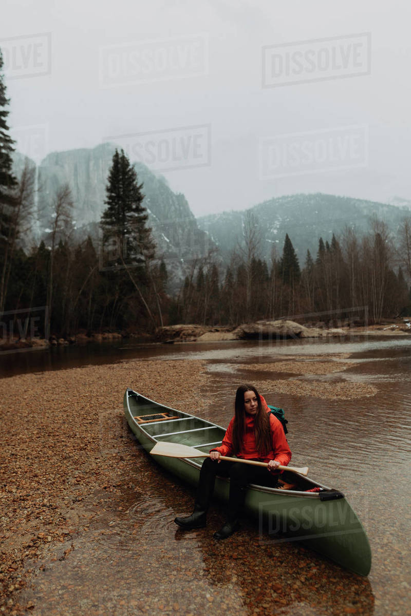 Young female canoeist sitting on canoe in river, Yosemite Village ...