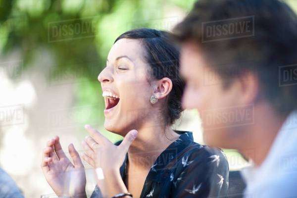 Woman laughing at table outdoors - Stock Photo - Dissolve