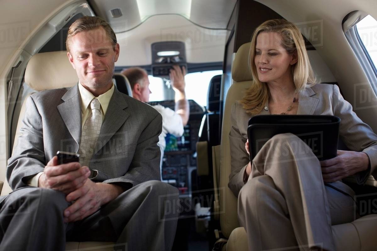 Business people talking in airplane - Stock Photo - Dissolve