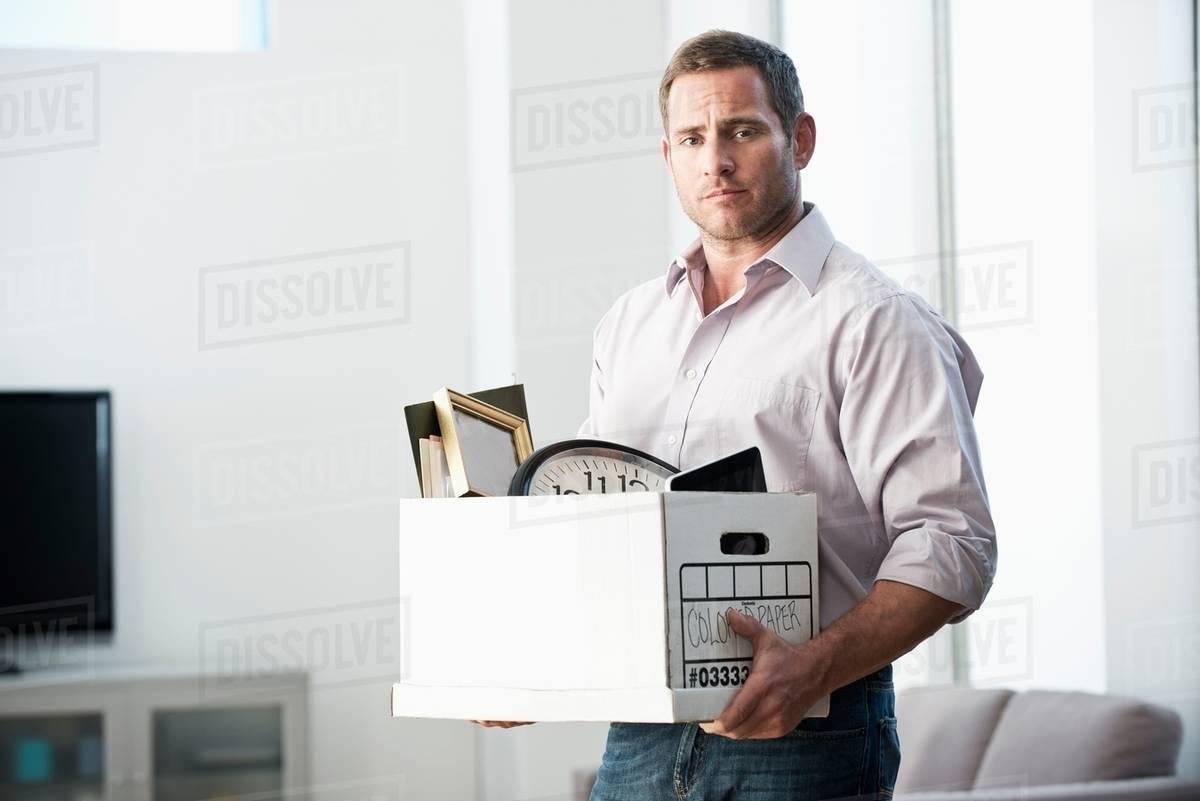 Businessman packing up box in office - Stock Photo - Dissolve