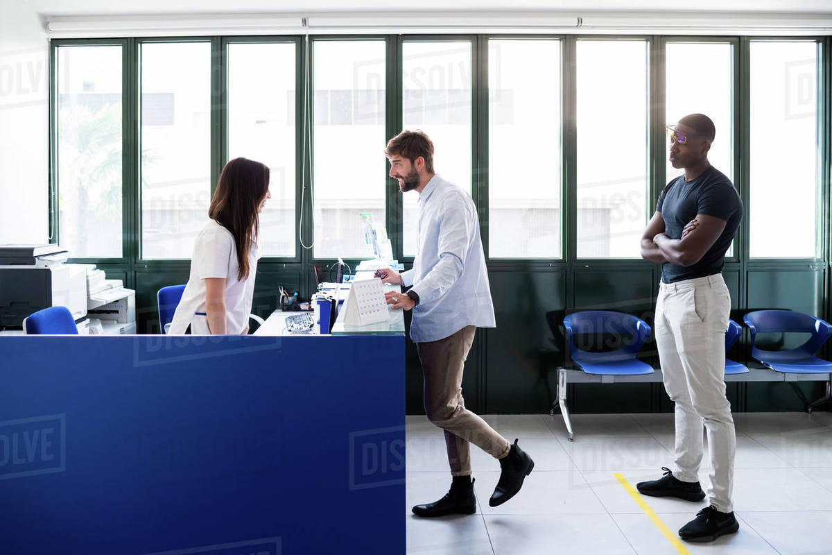 Nurse speaking with patients at hospital reception - Stock Photo - Dissolve