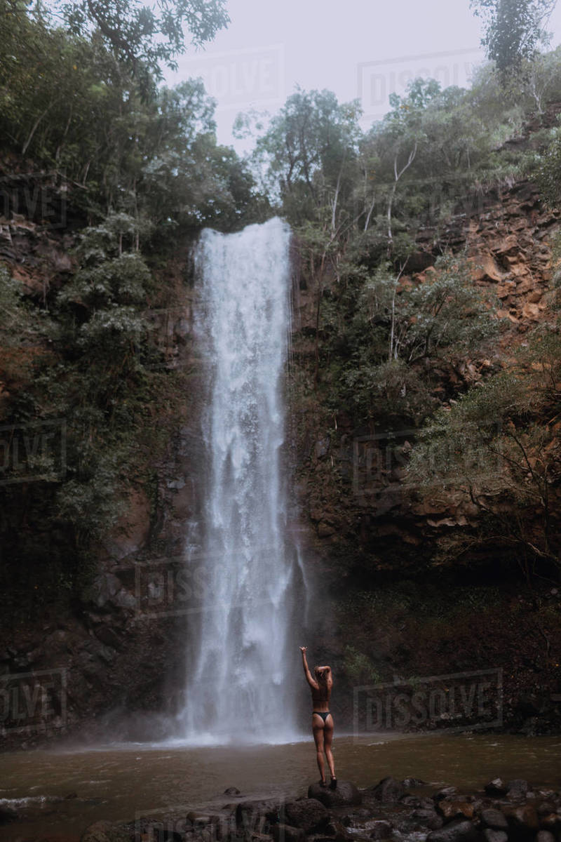Woman enjoying waterfall, Princeville, Hawaii, US - Stock Photo - Dissolve