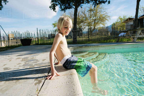 Boy sitting by swimming pool, Olancha, California, US - Royalty-free ...