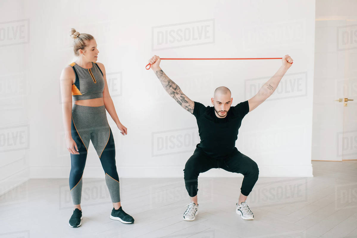 Woman observing fitness instructor using resistance band in studio ...