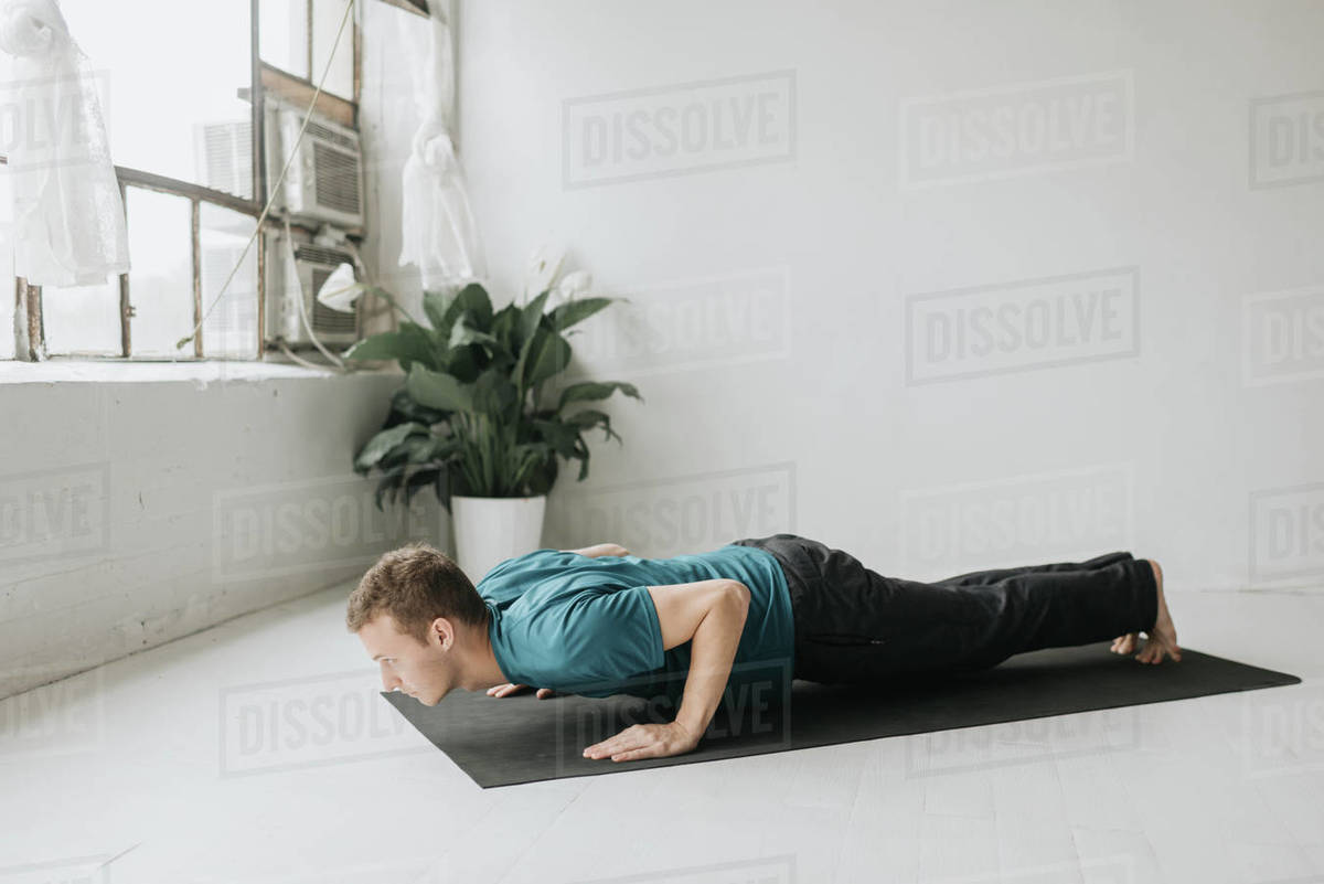 Man doing half plank in yoga studio - Royalty-free Stock Photo | Dissolve