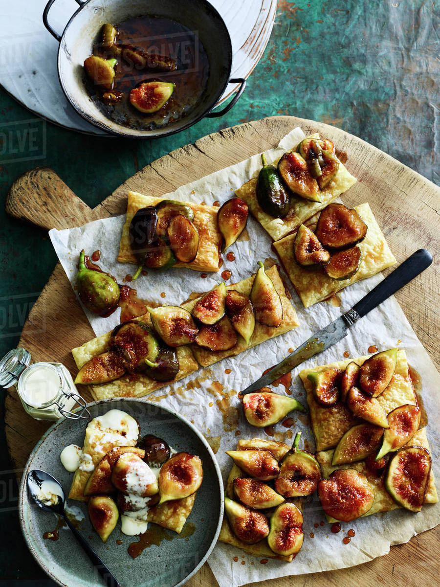 Pieces of figs on crackers served on cutting board - Stock Photo - Dissolve
